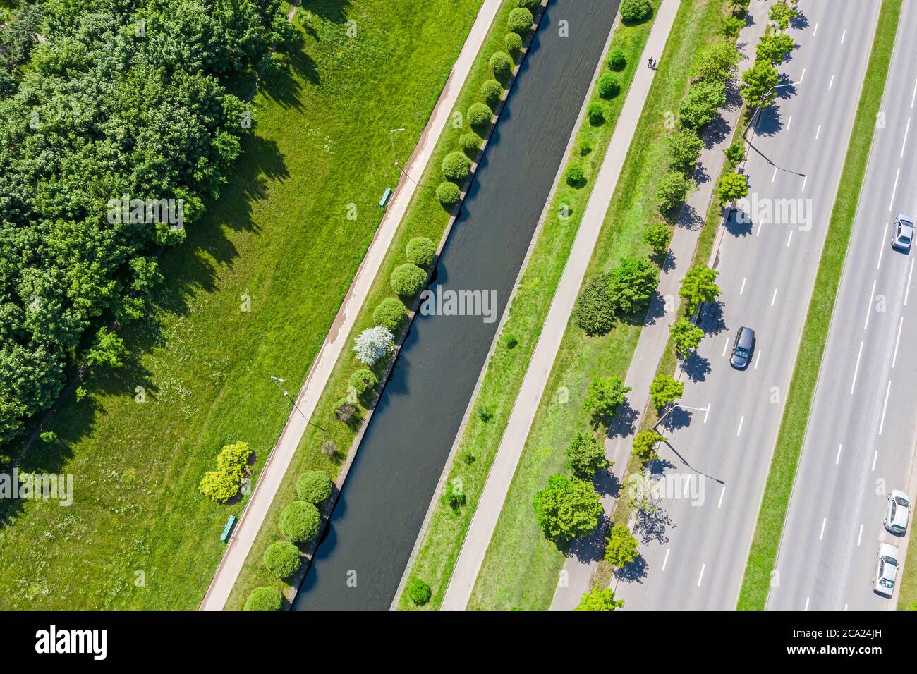 suburban landscape with green trees, lawn and water canal near city ...