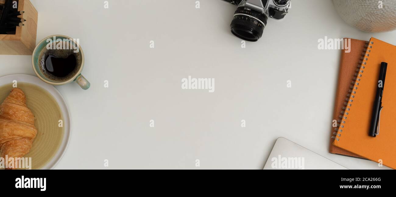 Top view of workspace with stationery, camera, decorations, pastry ...