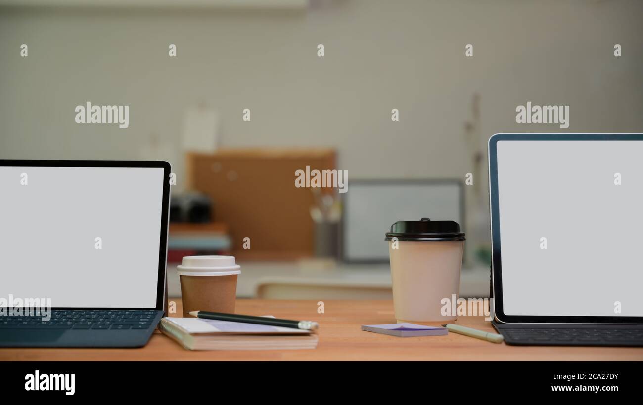Close up view of meeting table with two digital tablets, paper cup and ...
