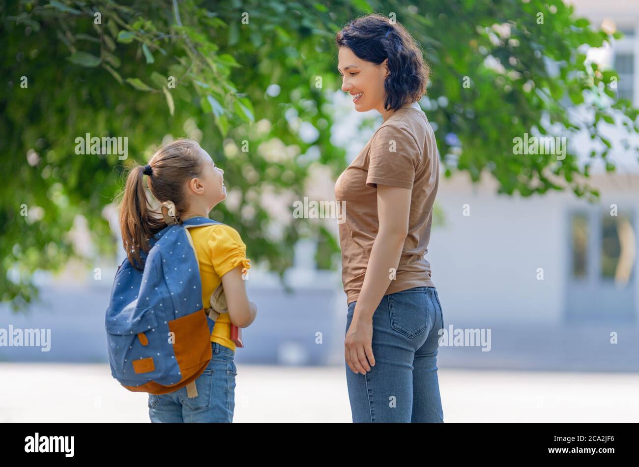 Parent and pupil of secondary school going hand in hand. Woman and girl ...