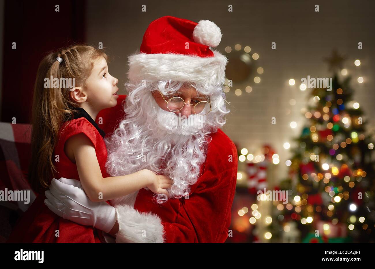 Santa listening to a little girl's wishes Stock Photo - Alamy