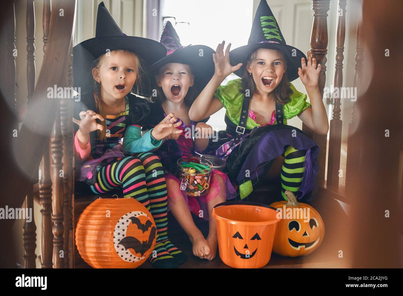 Happy Halloween! Three cute little laughing girls in witches costumes ...