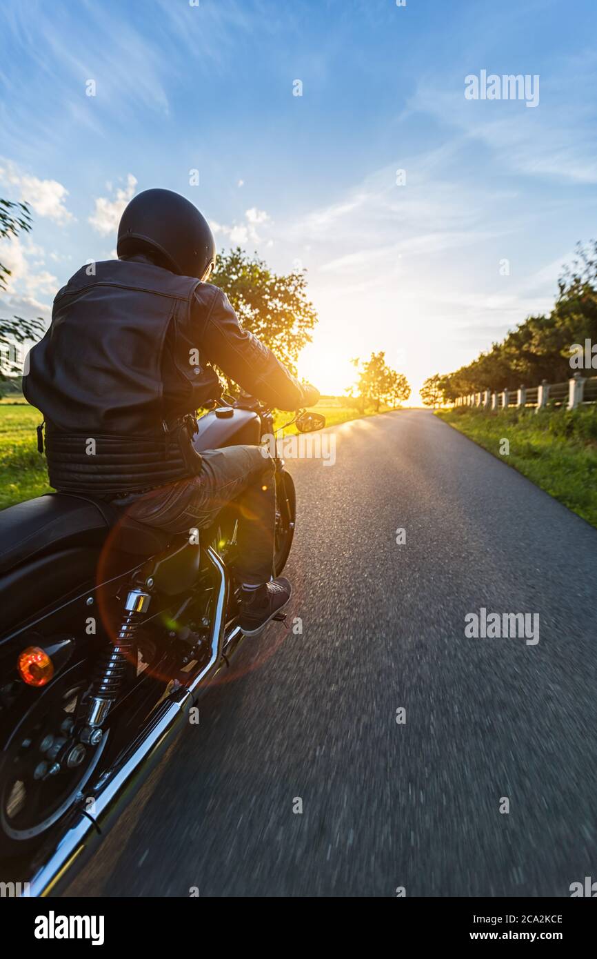 Dark motorbiker riding high power motorbike in nature with beautiful ...