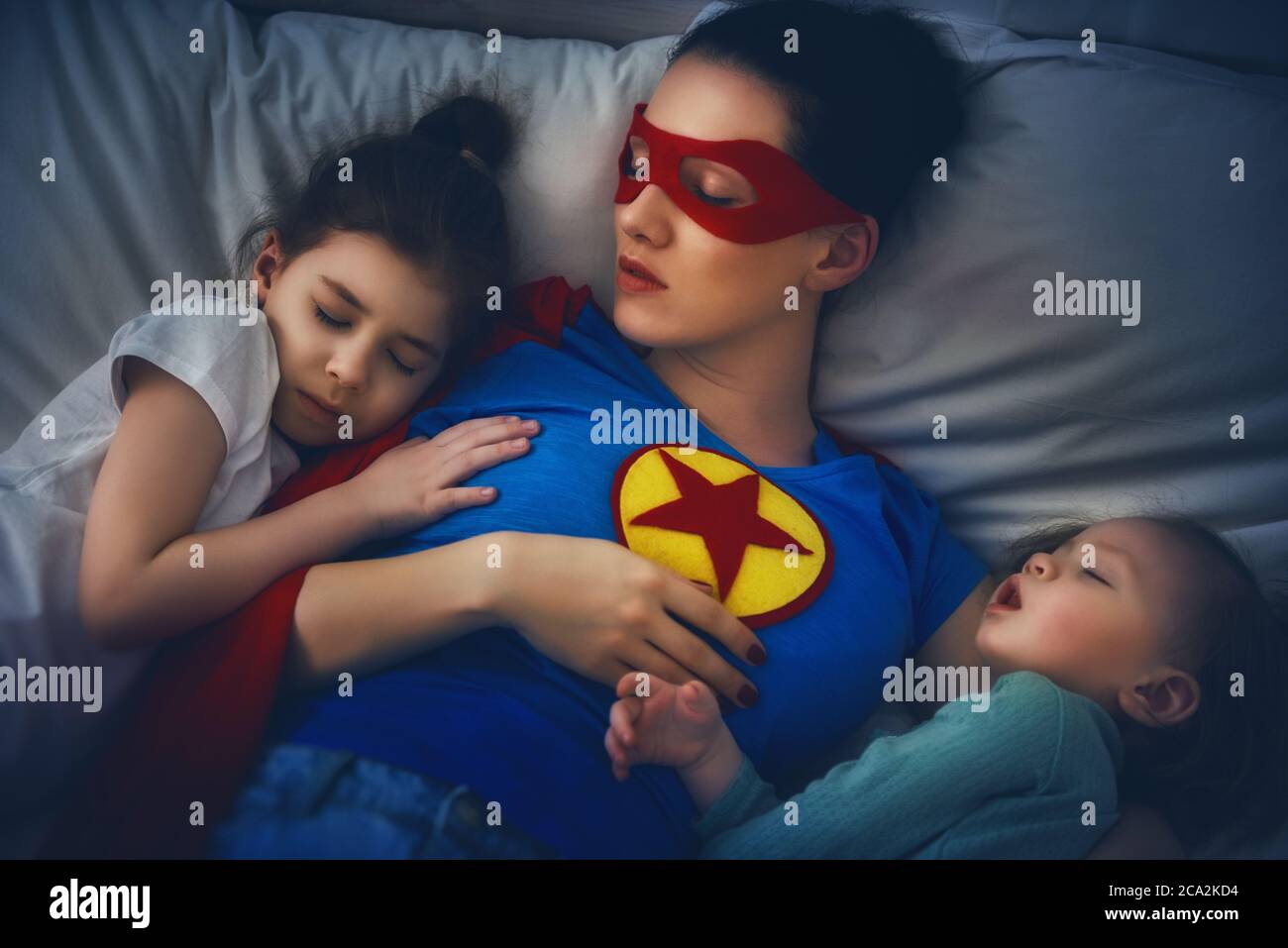 Adorable little children girls are napping in the bed with their mom ...