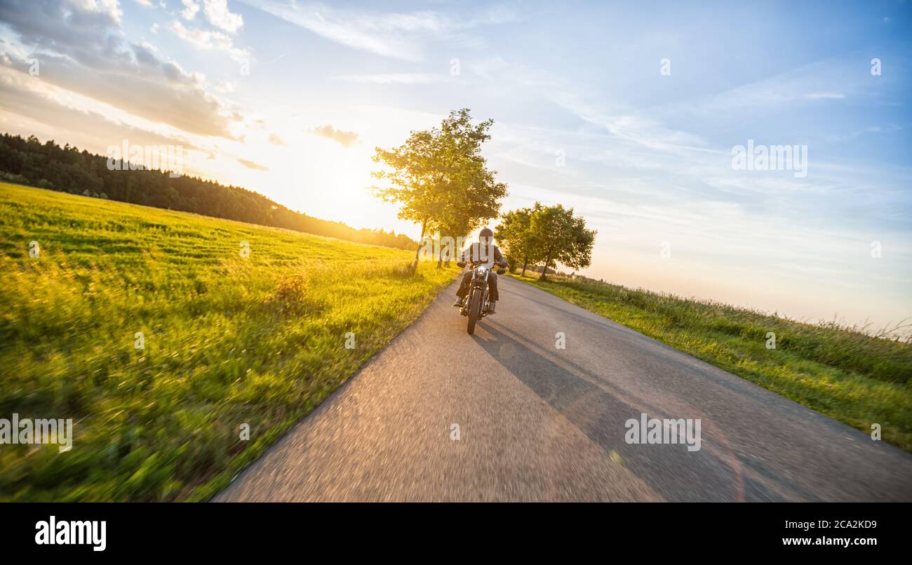 Dark motorbiker riding high power motorbike in nature with beautiful ...