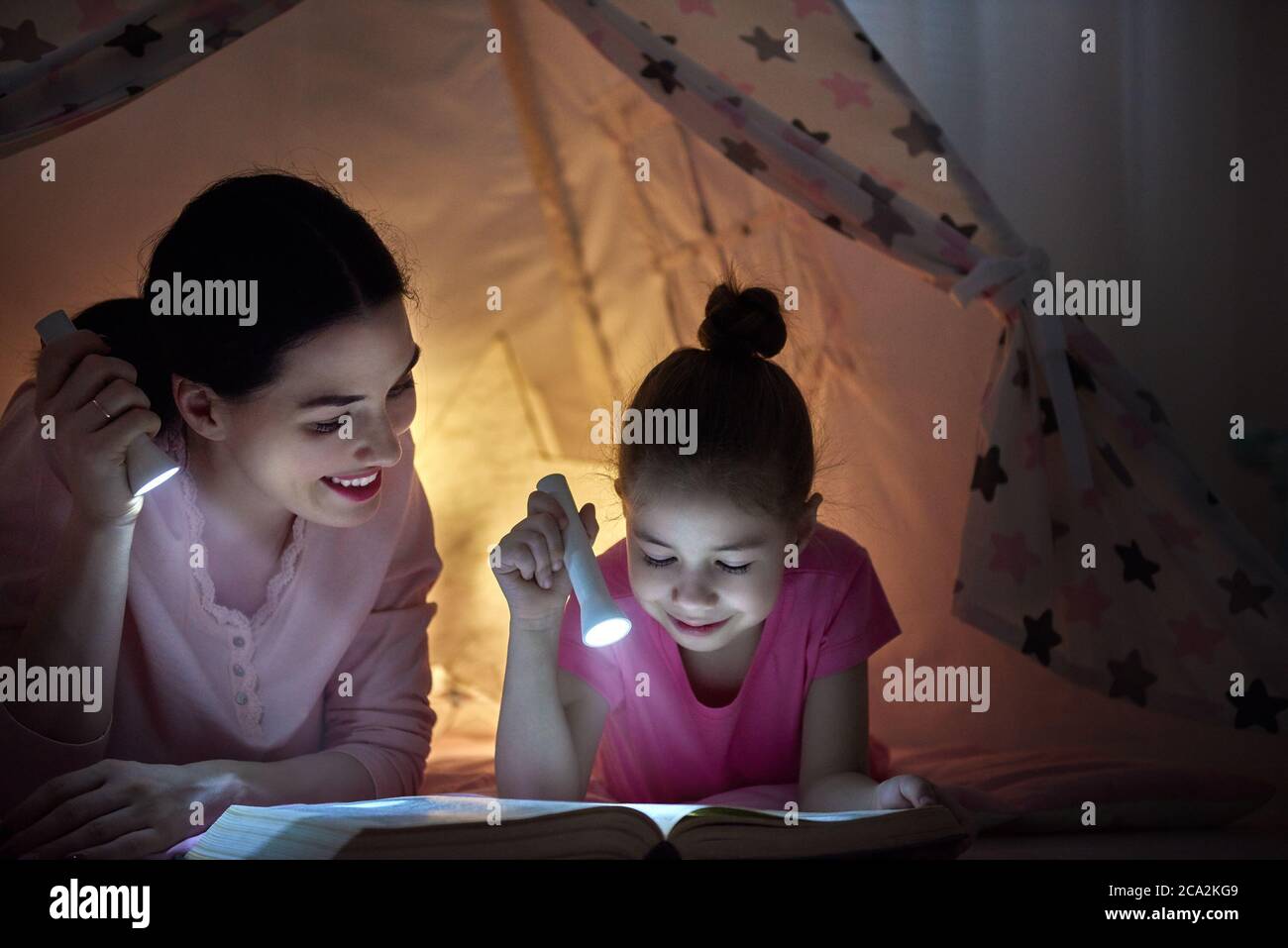 Family bedtime. Mom and child daughter are reading a book with ...