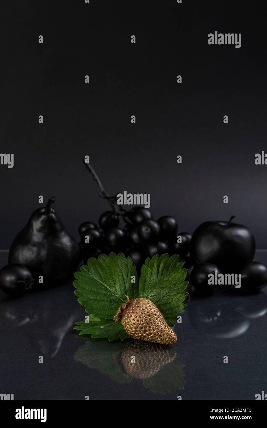 Conceptual image of black fruits on gray reflective surface with a ...