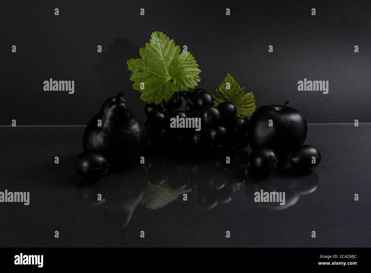 Conceptual image of black fruits on gray reflective surface Stock Photo ...