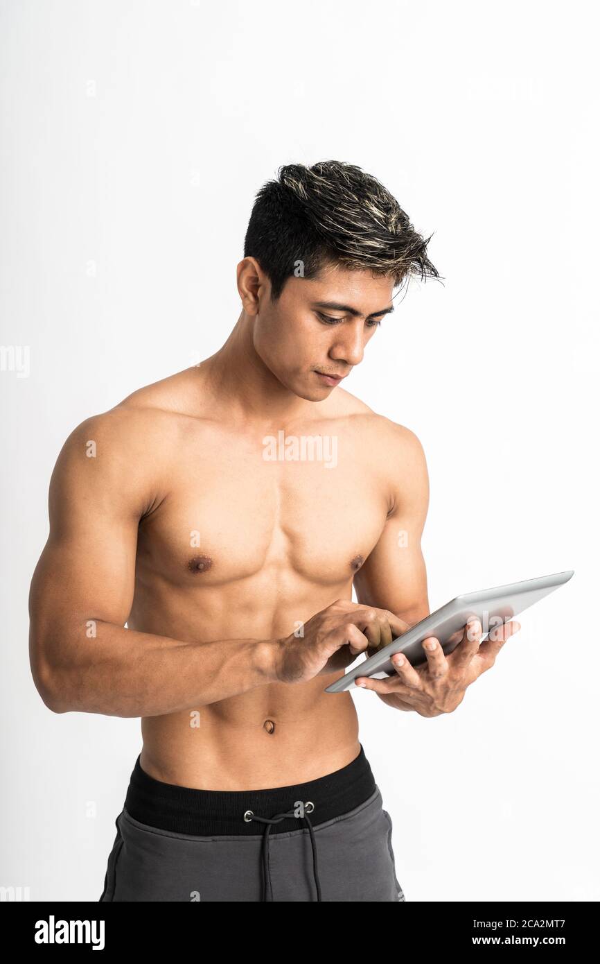 asian young man with muscular body holding a tablet with two hand ...