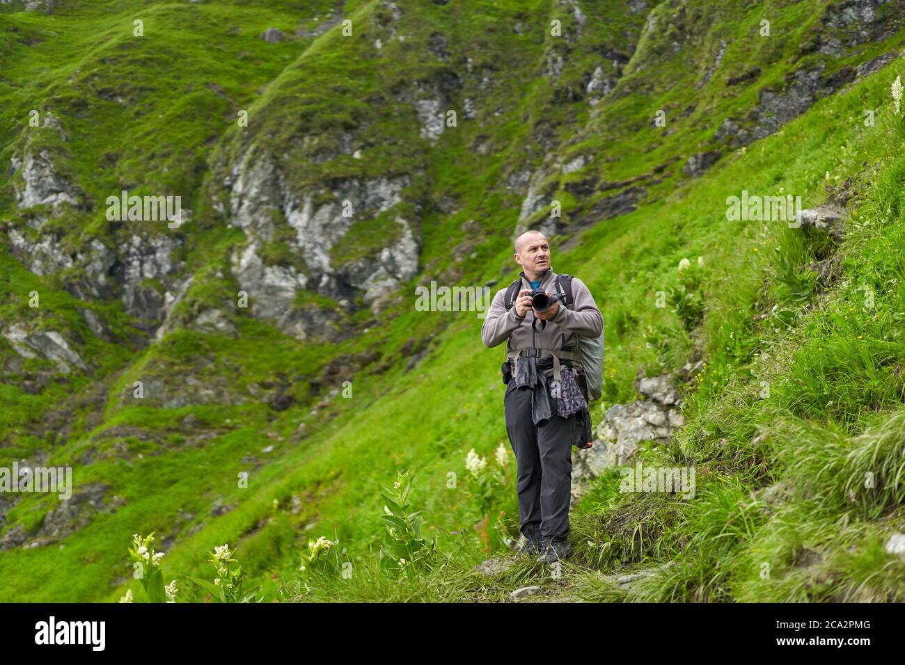 Professional nature photographer with camera and big backpack hiking ...