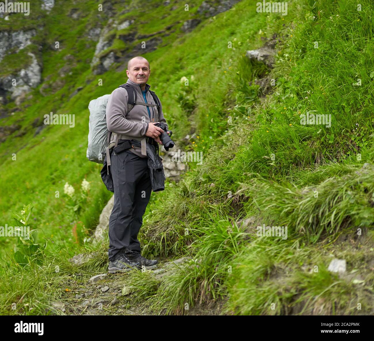 Professional nature photographer with camera and big backpack hiking ...