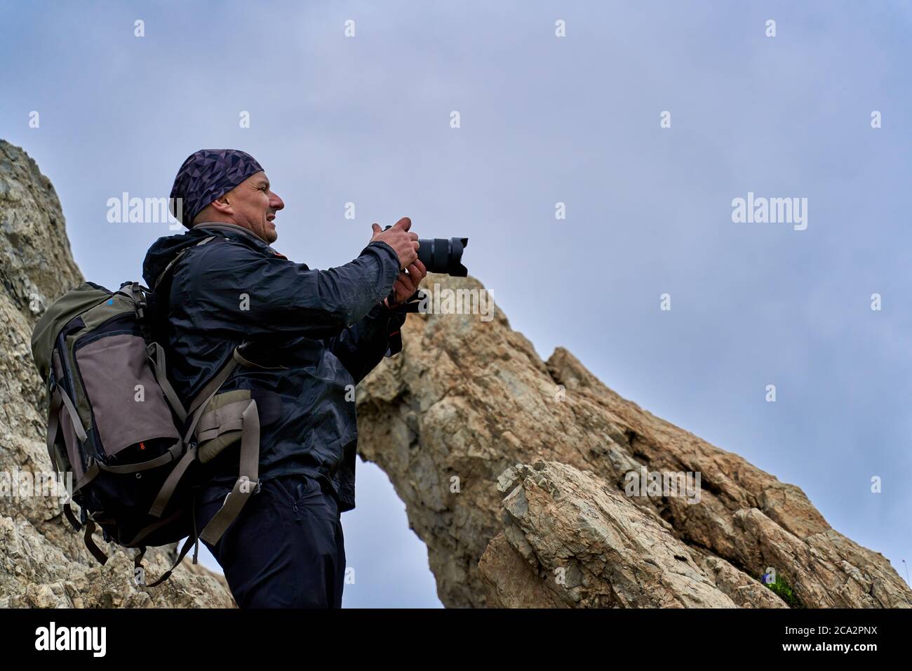 Professional nature photographer with camera and big backpack hiking ...