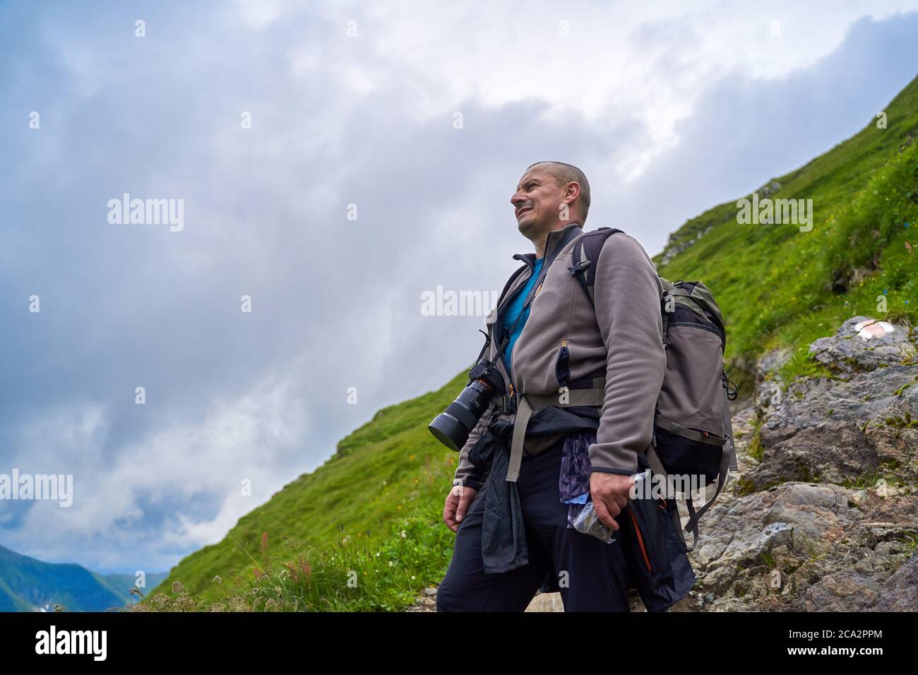 Professional nature photographer with camera and big backpack hiking ...
