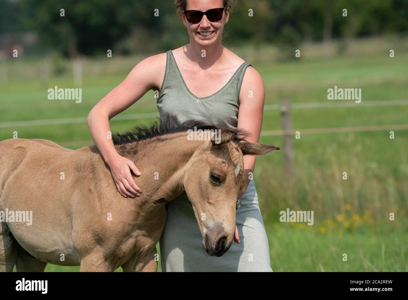Young woman cuddling with her best friend, falcon color stallion foal ...