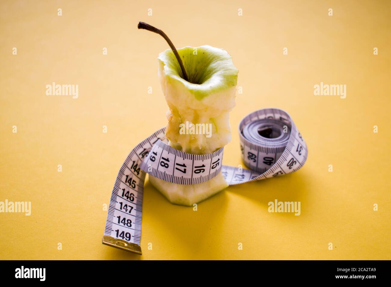 Eaten apple with white measuring tape on yellow background Stock Photo ...