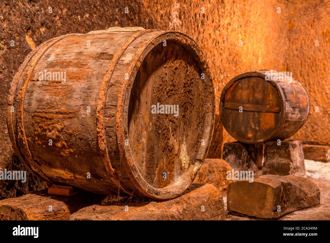 Old oak barrel with rusty hoops. Deep wine cellar with textured walls ...