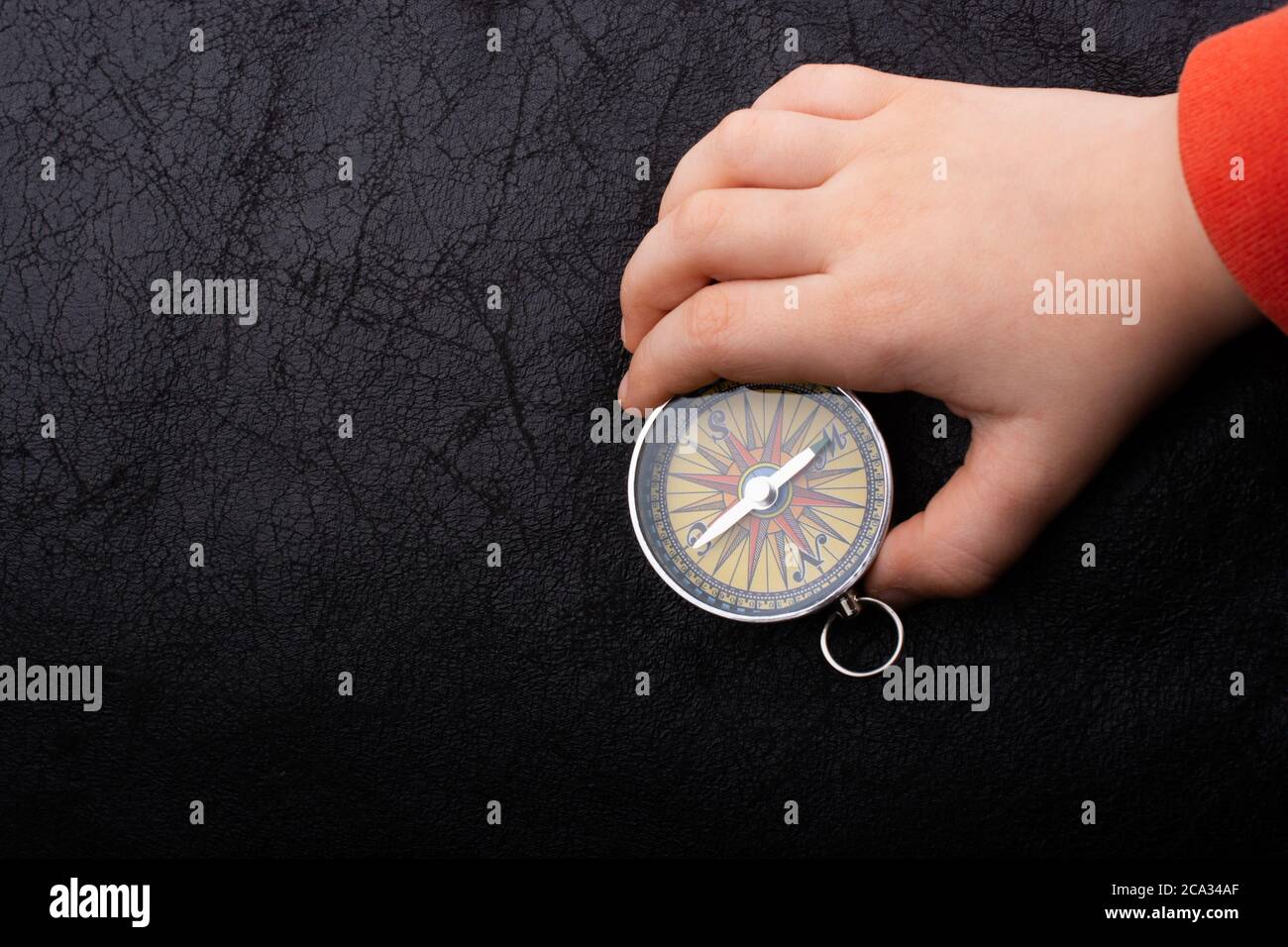 Hand is holding a magnetic compass on black background Stock Photo - Alamy