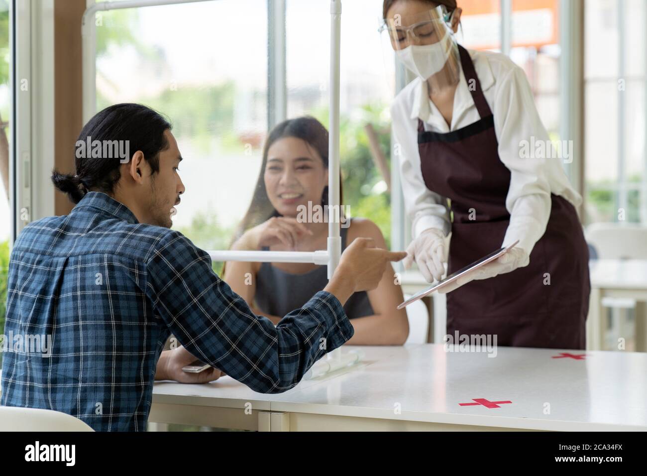 Asian waitress wear face mask and face shield using tablet to show ...