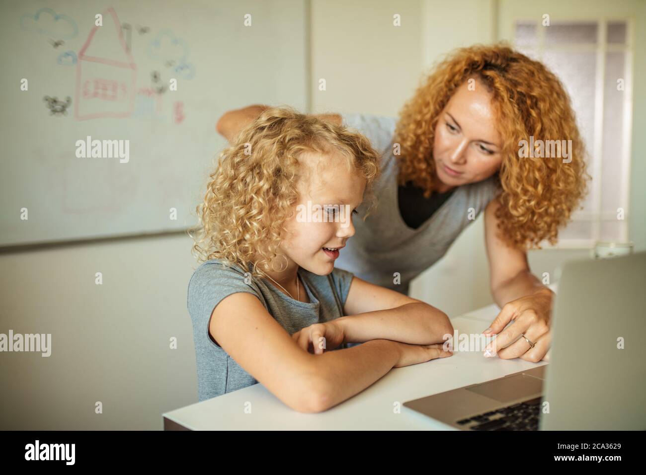 Smiling attractive caucasian female tutor helps her adorable little ...