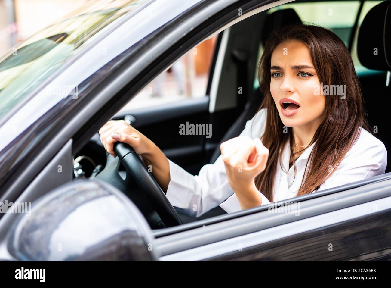 Angry woman driver threatens other drivers with a fist. Traffic jams ...