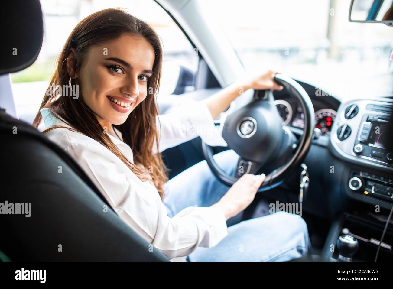 Lifestyle shot of young cheerful woman driving car - rear view Stock ...