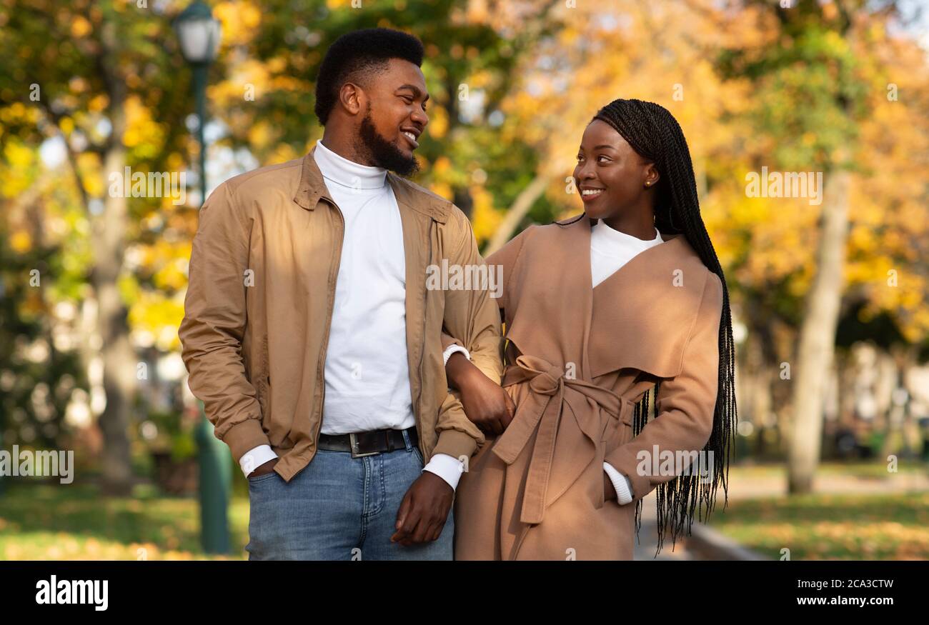 Portrait of black millennial couple walking together in autumn park ...