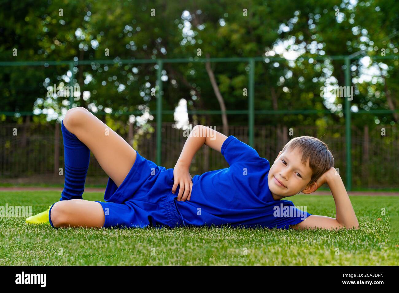 a small football player is lying on a green football field Stock Photo ...