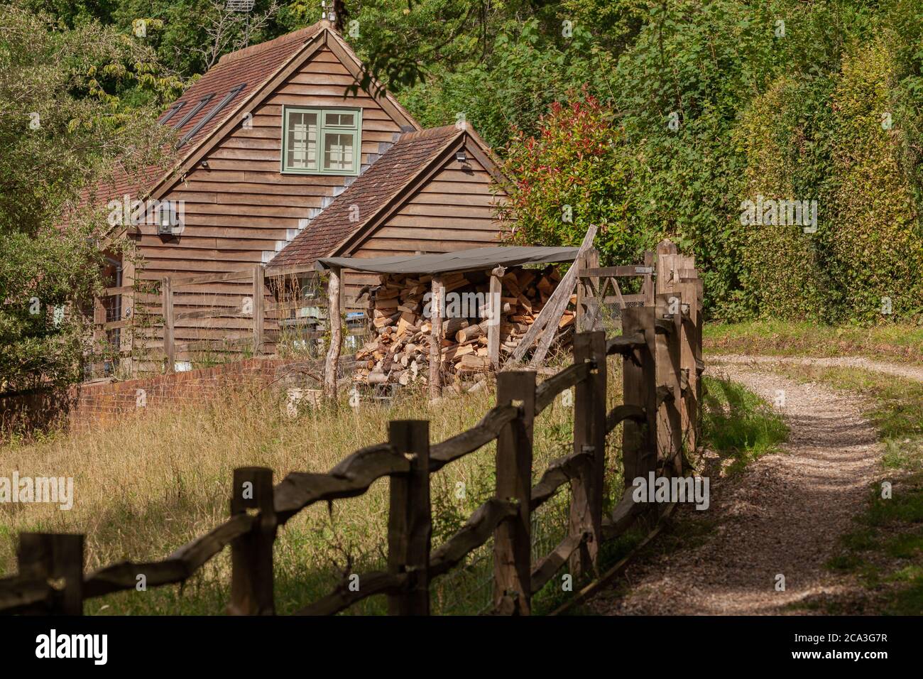 A quaint fairytale wooden cottage, covered by lush plant life and ...