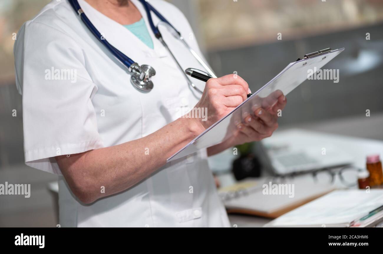 Female doctor taking notes on clipboard in medical office Stock Photo ...