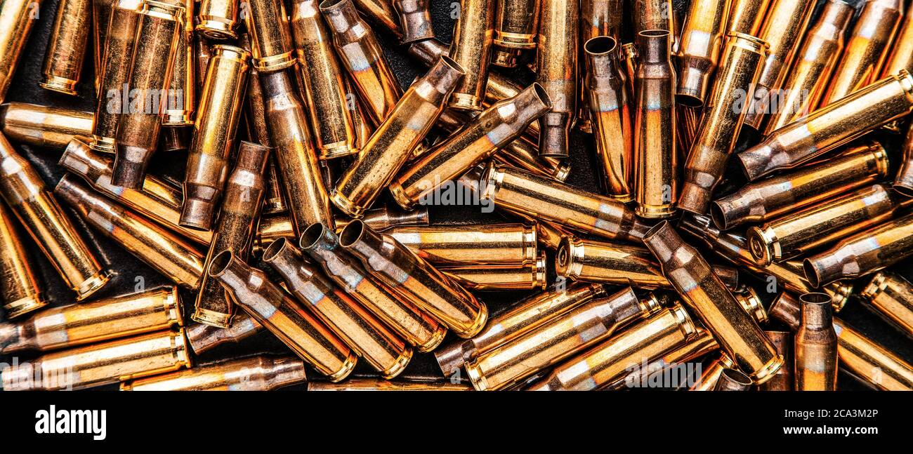 Empty cartridge cases for a carbine or rifle. Background of shiny brass ...
