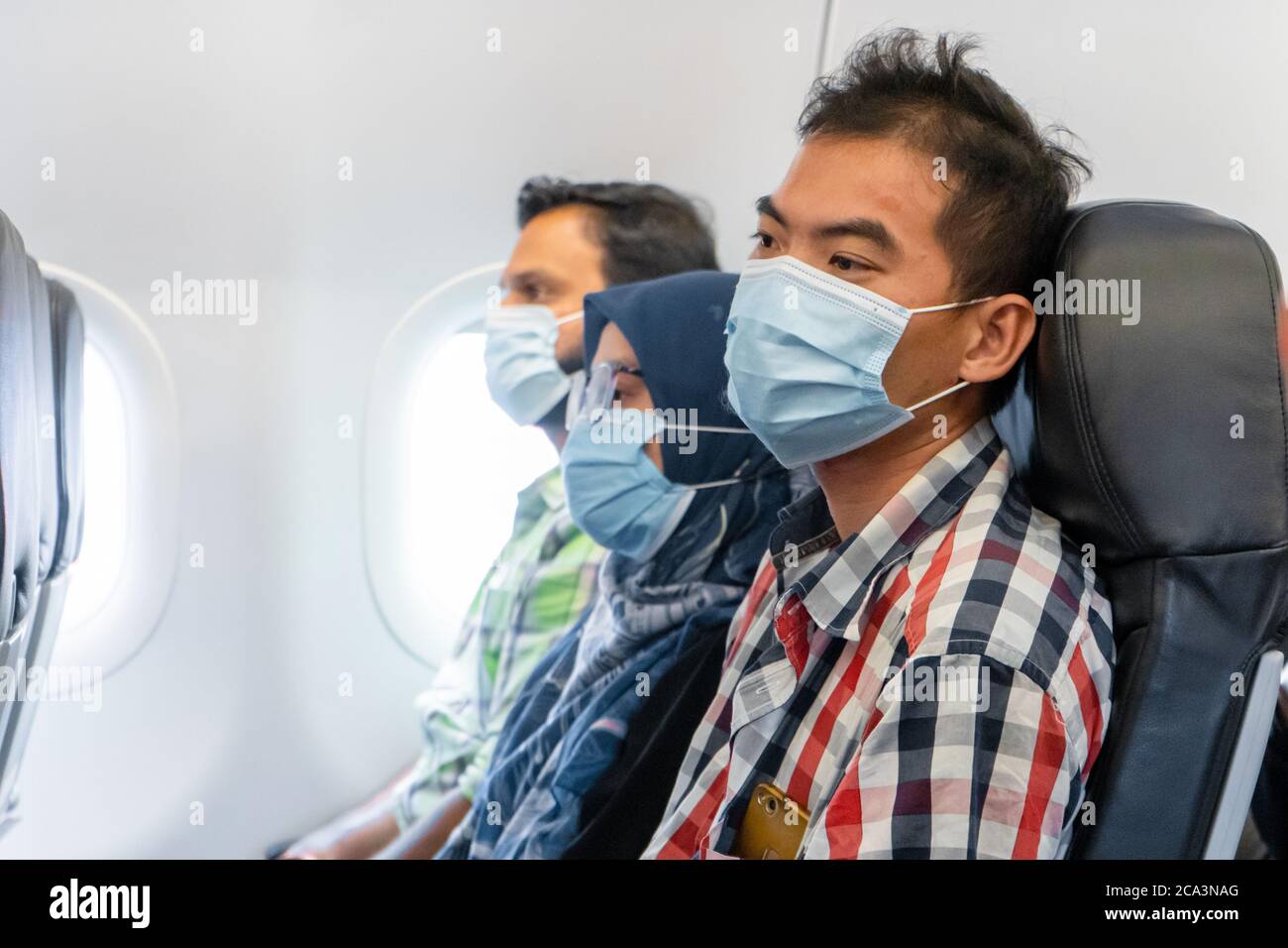 Airplane passengers are wearing medical masks on their faces. Air ...