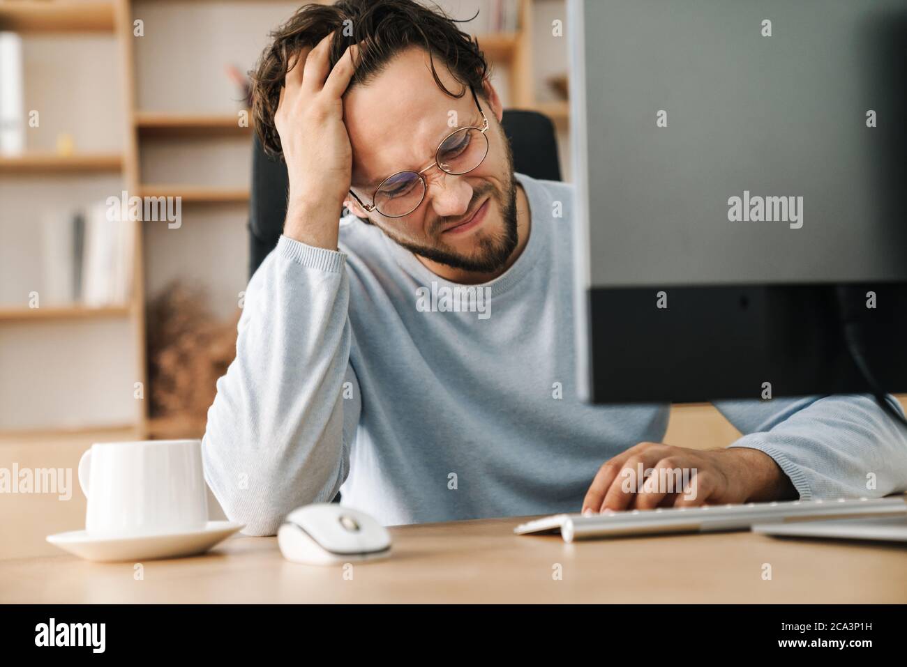 Image of unhappy bearded programmer man wearing eyeglasses working with computer in office Stock ...