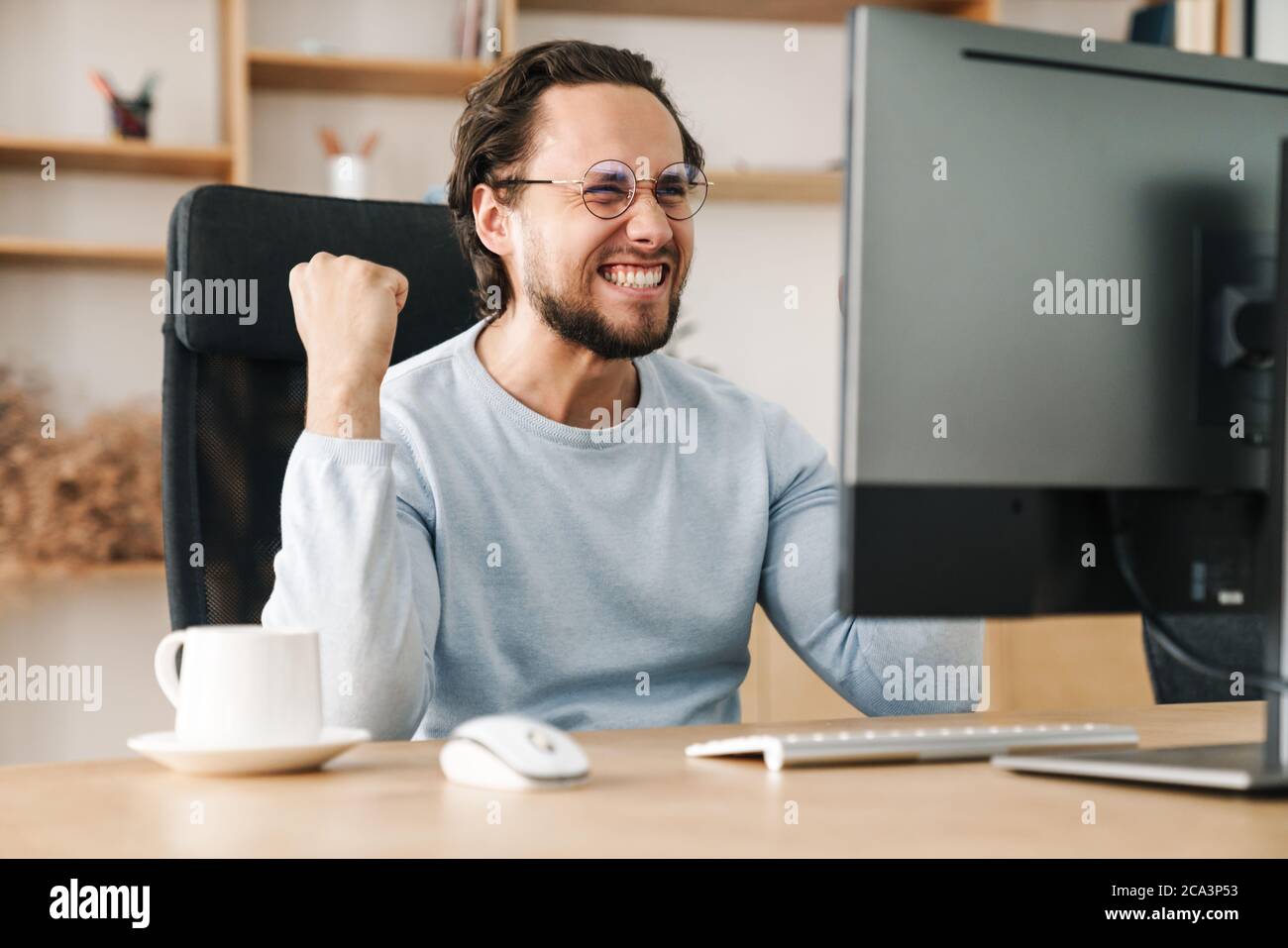 Image of laughing programmer man making winner gesture while working ...