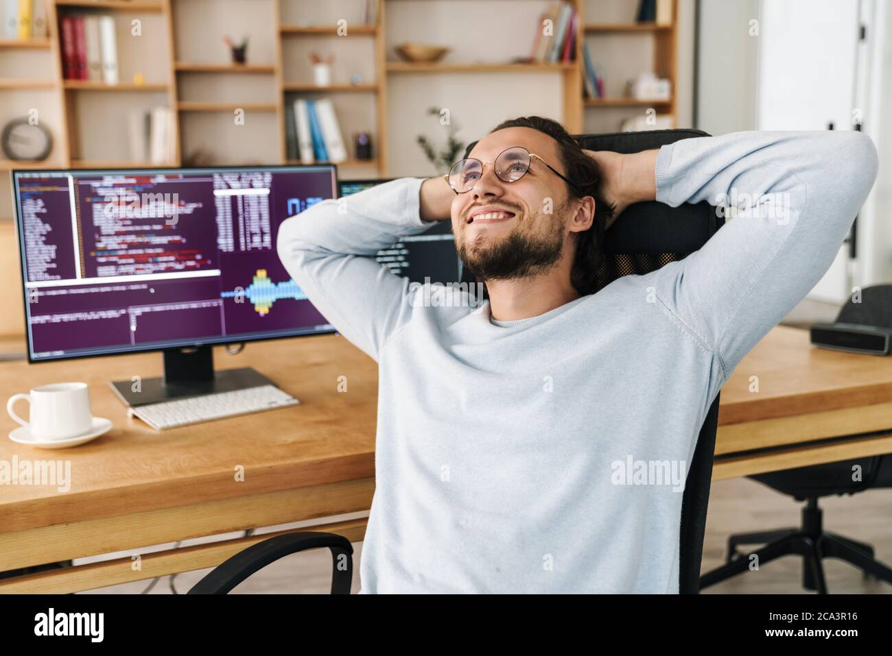 Image of handsome joyful programmer man smiling and resting while ...