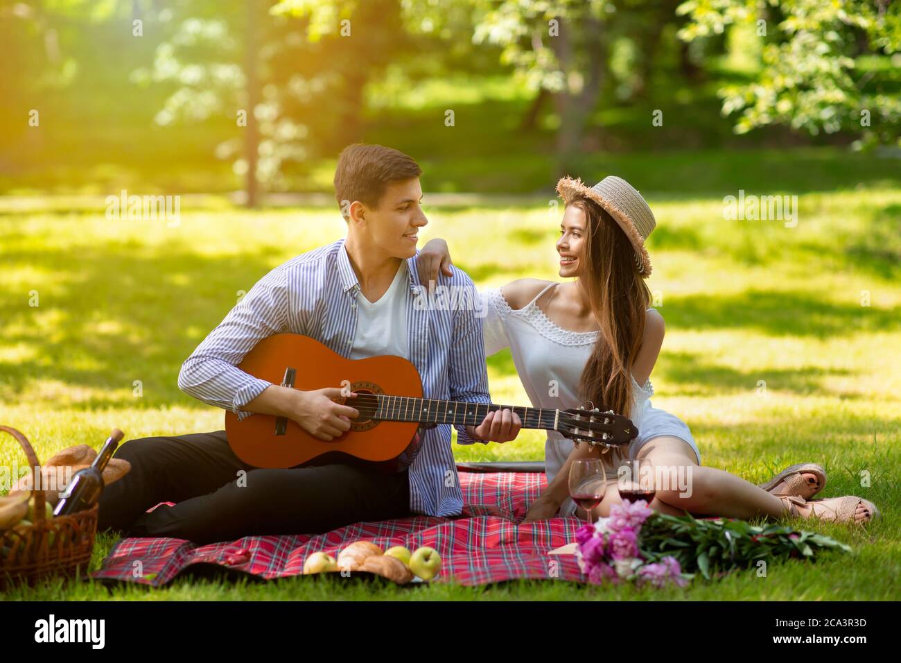 Handsome young guy singing song and playing guitar to his beloved woman ...