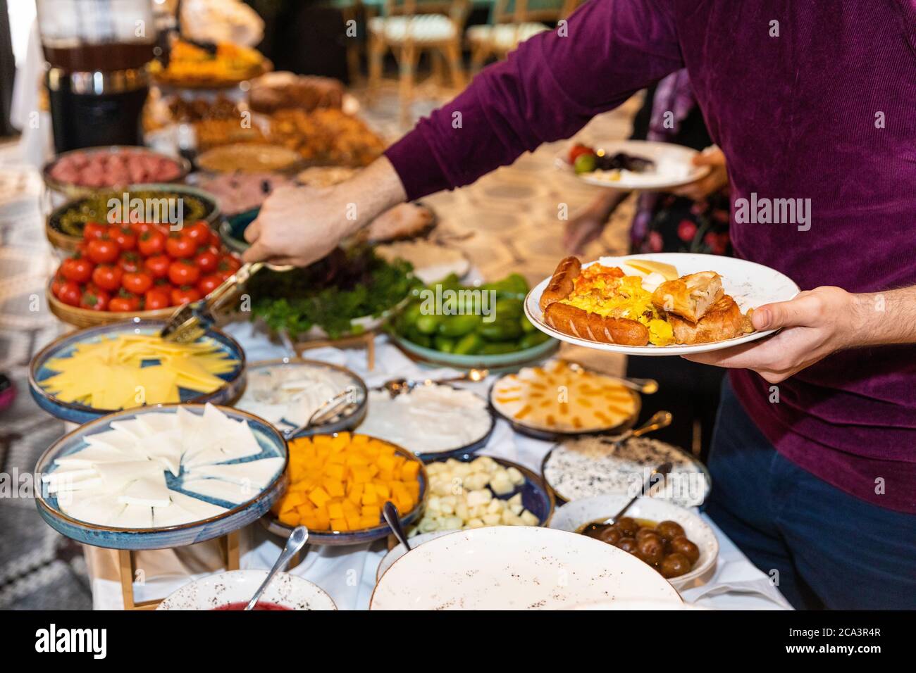 Man taking food from breakfast table at the restaurant Stock Photo - Alamy