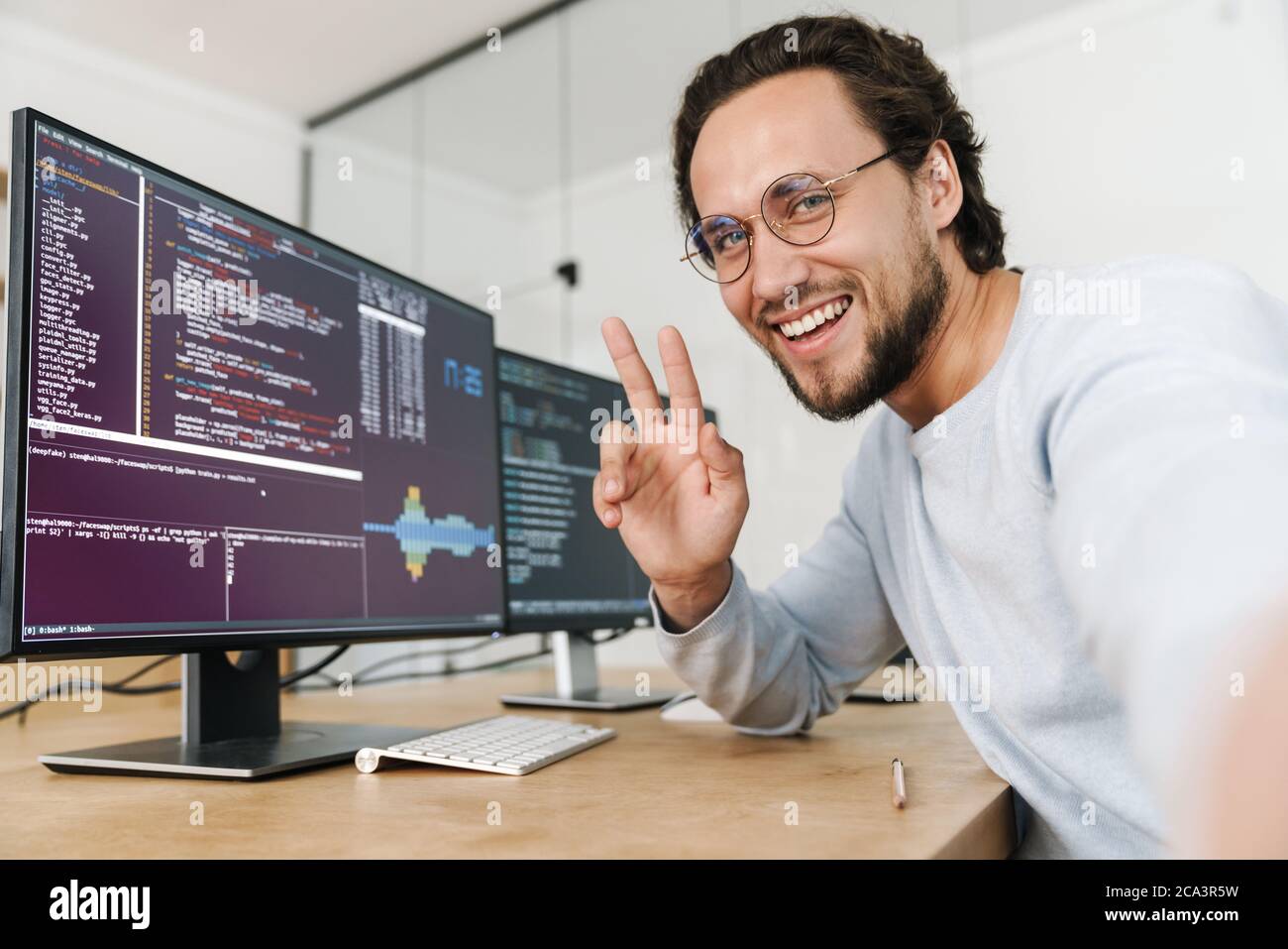 Image of smiling unshaven programmer man showing peace sign while ...