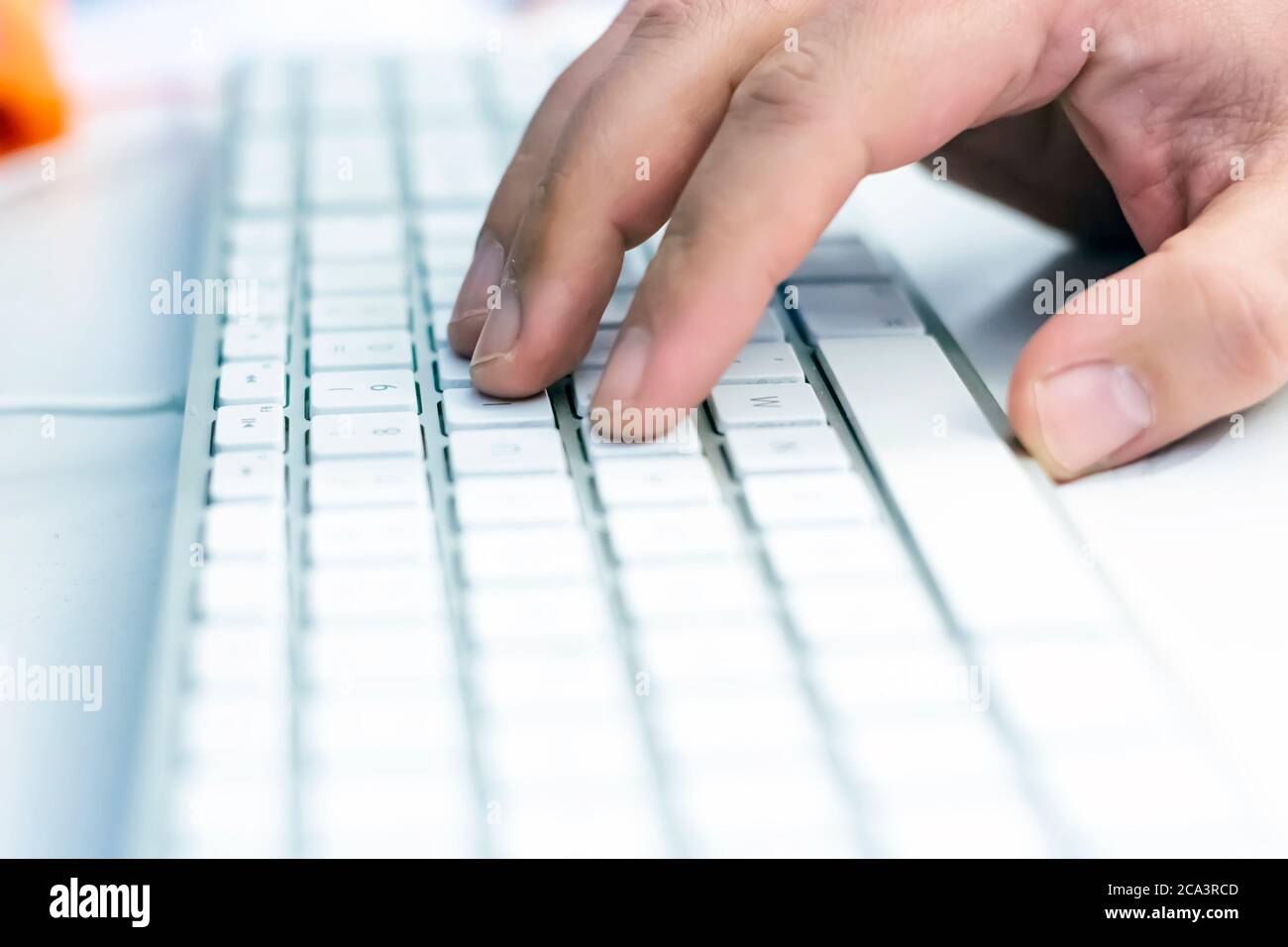 a male hand over the white keyboard of a computer before typing. Work ...