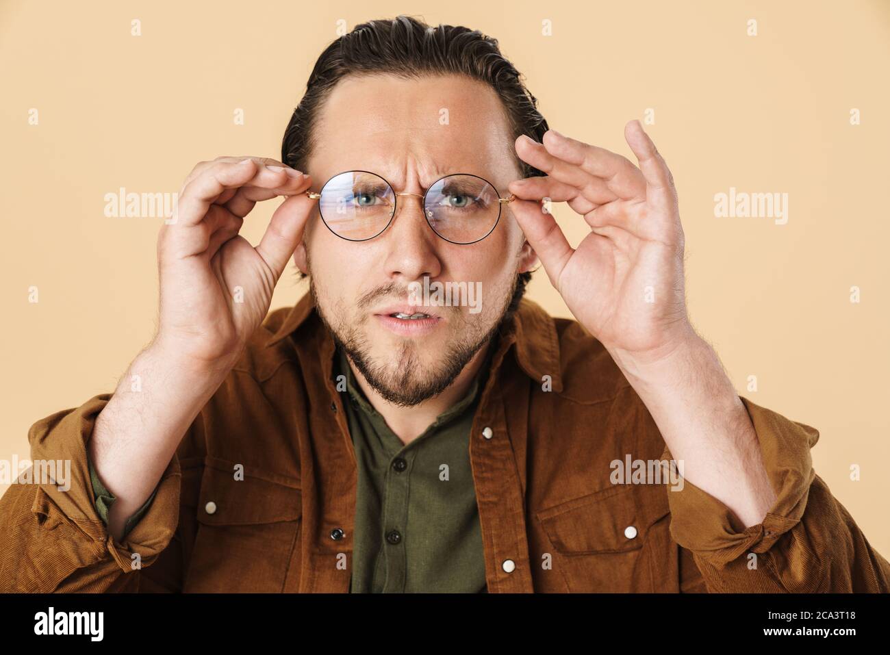 Image of young confused man wearing eyeglasses looking at camera ...