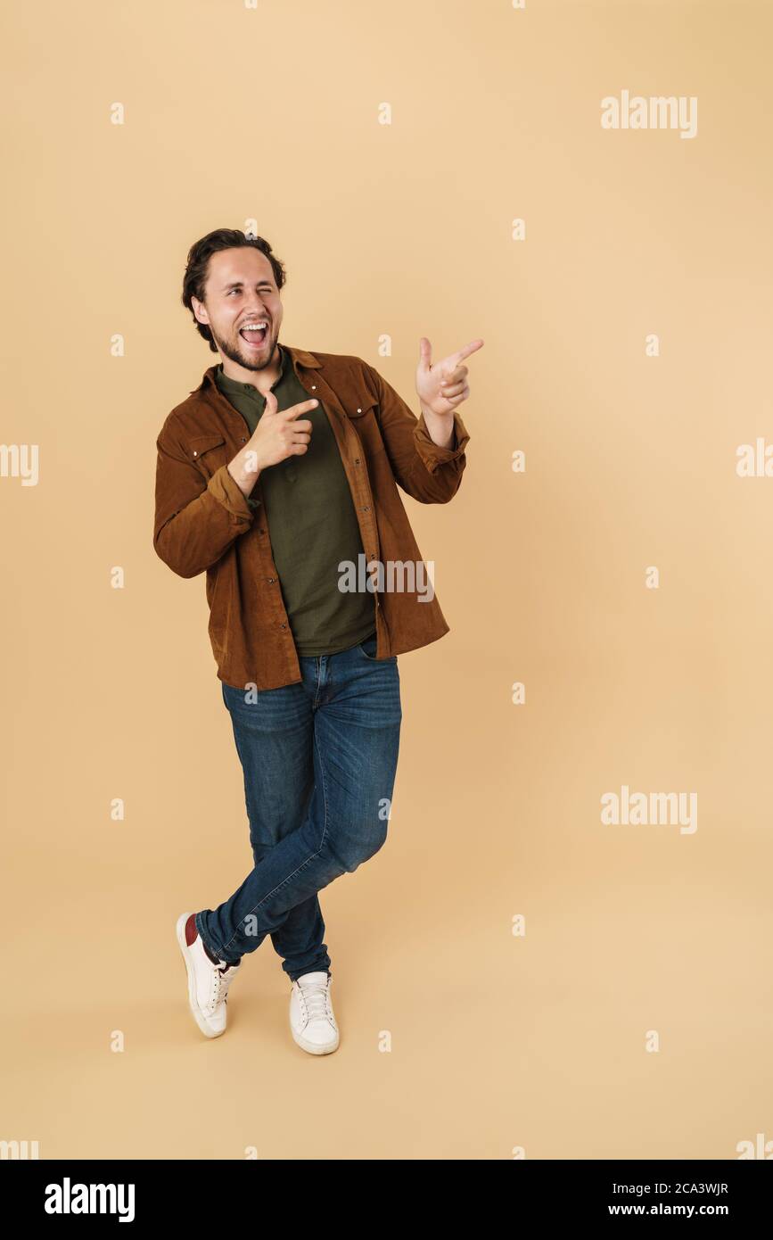 Image of handsome cheerful man winking and pointing fingers aside ...