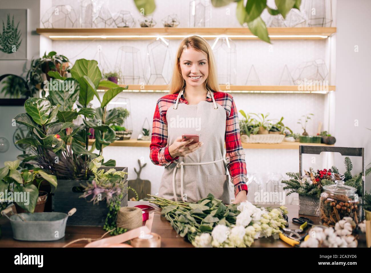 young attractive gardener at work, take care of green plants, enjoy ...