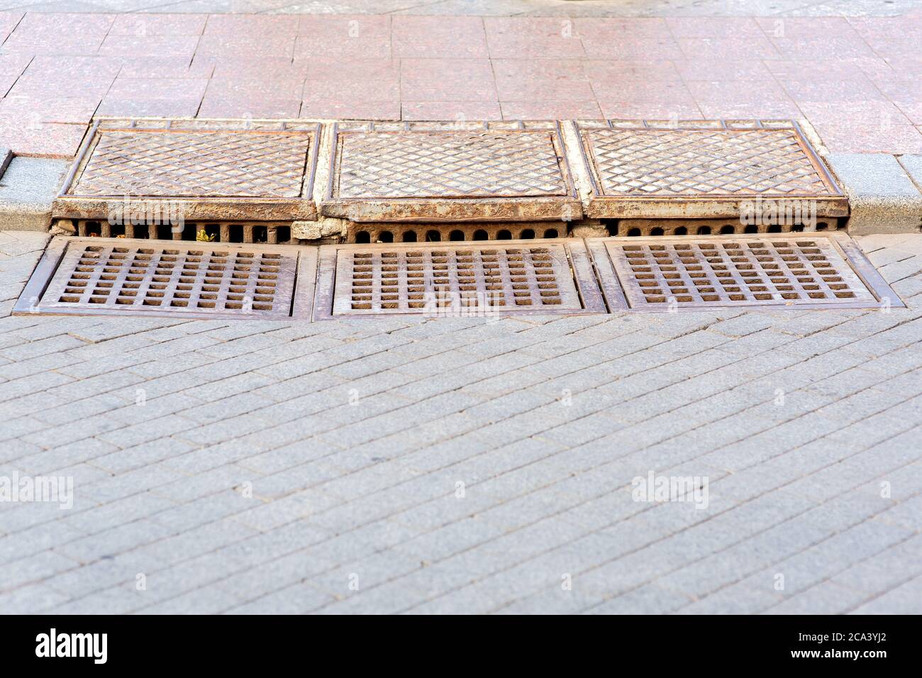 square manhole drainage system grille on the road curb with pedestrian ...