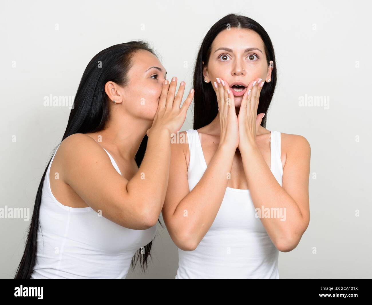 Portrait of two beautiful women whispering together Stock Photo - Alamy