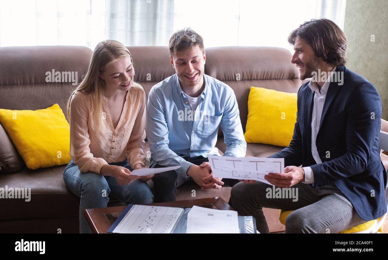 Happy couple with property manager looking at house plan indoors Stock ...