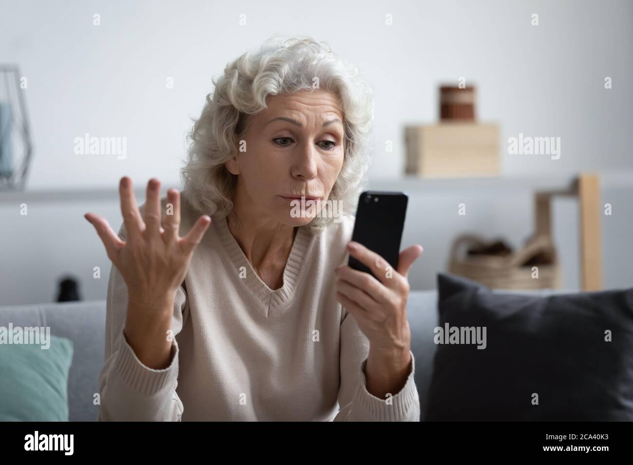 Grandmother holding smartphone looks at device screen feels angry Stock ...