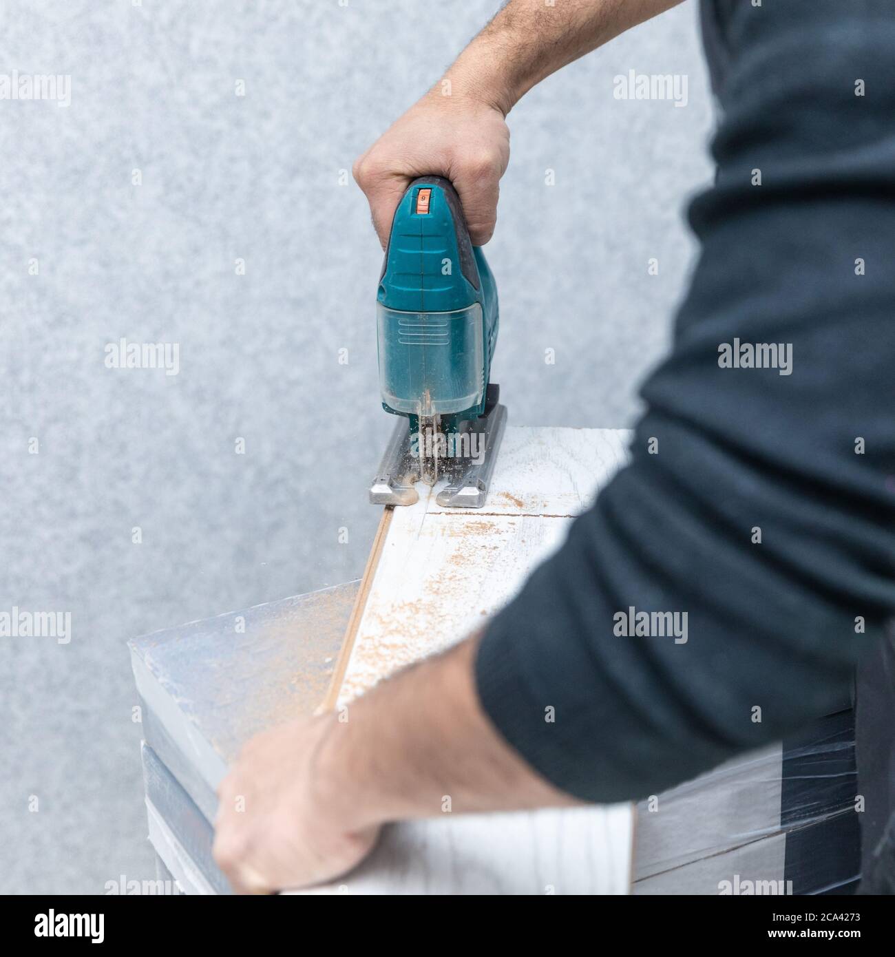 Man working with jigsaw on white wood laminate Stock Photo - Alamy