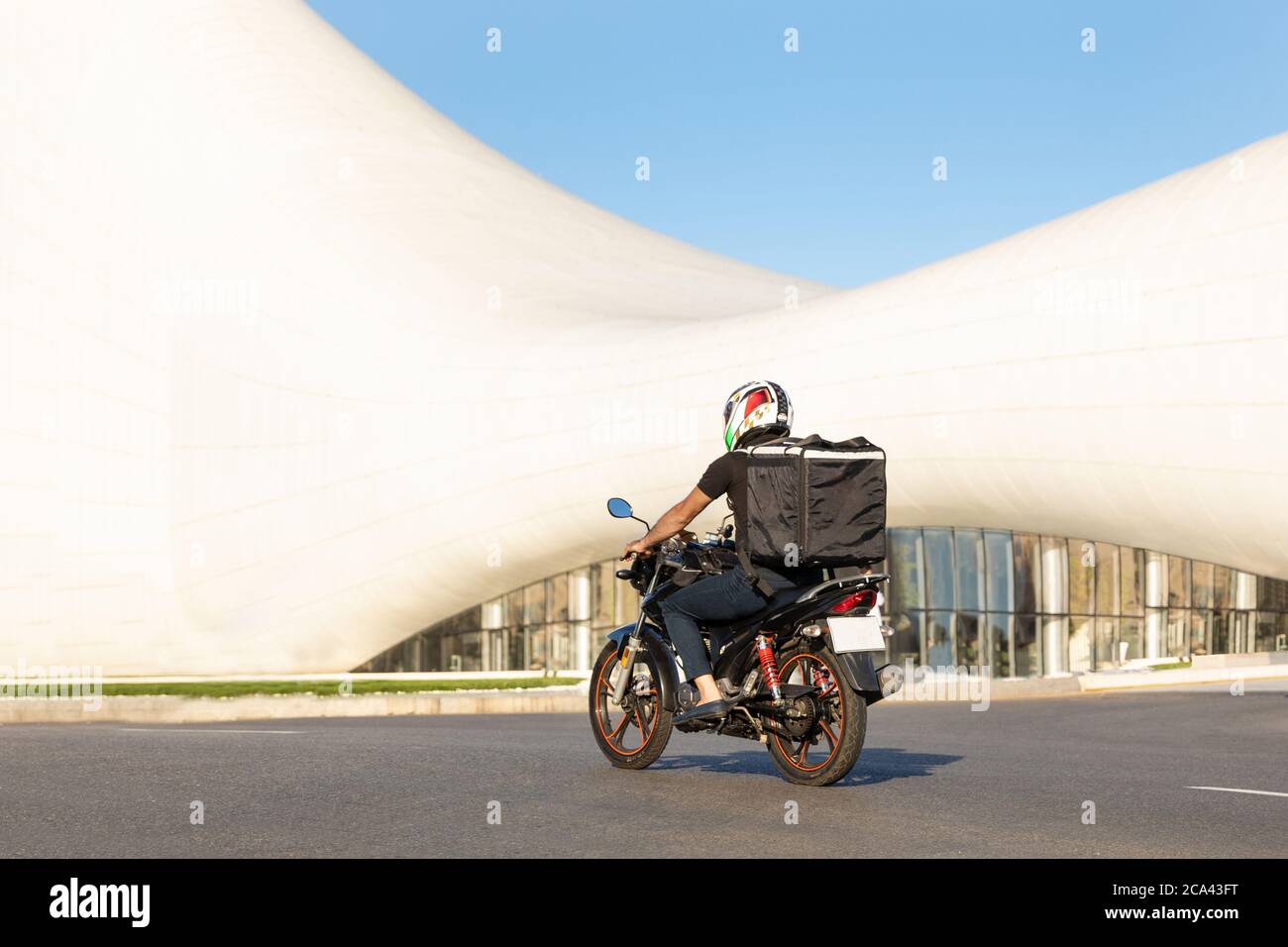 Courier worker driving a motorcycle in the city Stock Photo - Alamy