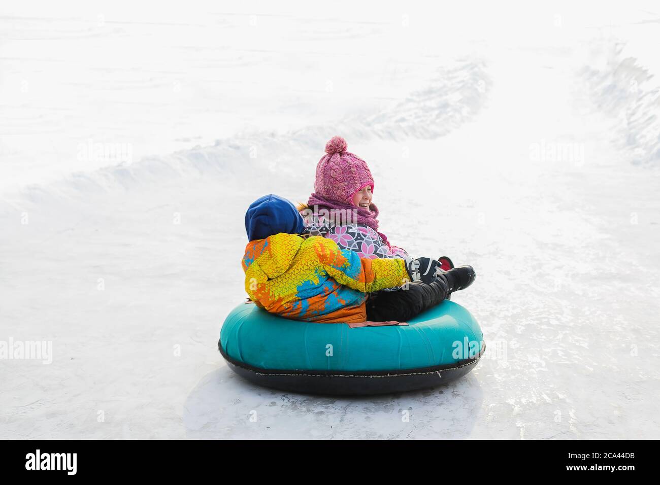 Little kids roll down the ice slide on tubing. Wintertime. Fun and ...