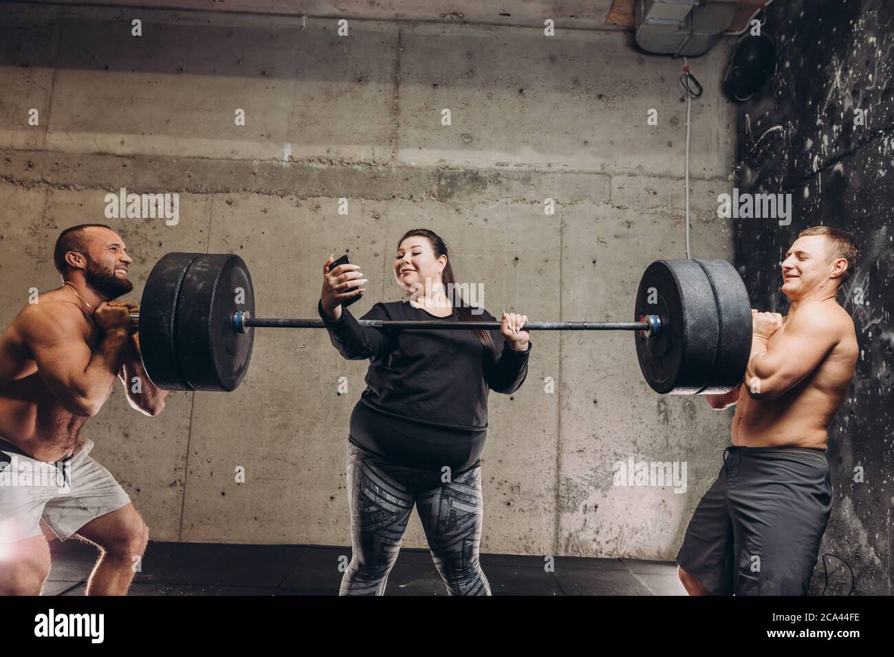 crazy fat girl taking a picture of herself while sportsmen lifting the ...