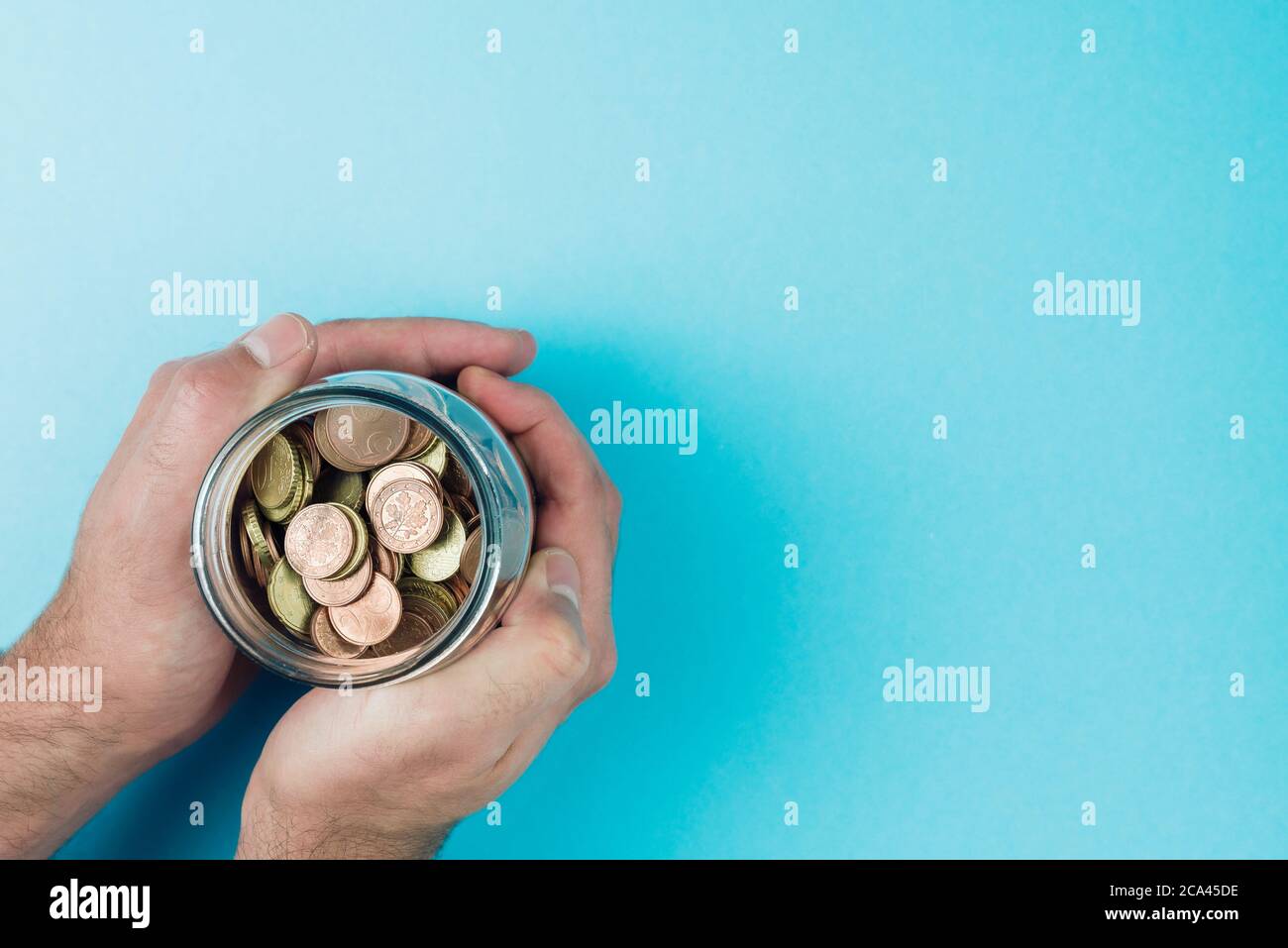 above view of hands holding jar filled with small change, savings and ...